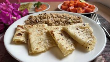 Um prato com três wraps, uma tigela de arroz e um prato de legumes picados.