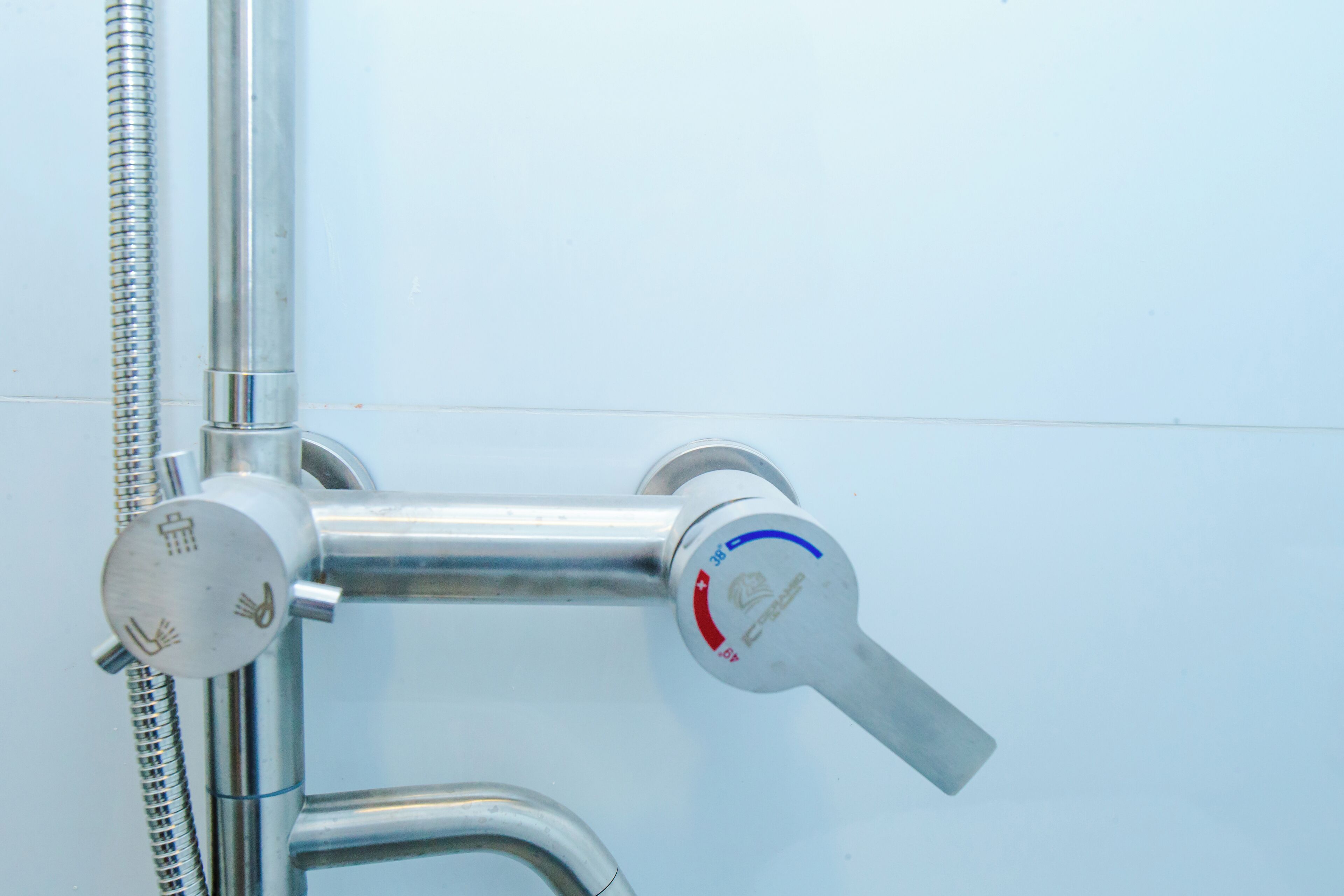 Uma válvula de controlo de chuveiro com um botão para ajustar a temperatura e uma alavanca para controlar o fluxo de água.