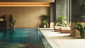 Uma área interna de piscina moderna, com vista clara para a piscina, espaço para sentar e plantas em vasos.