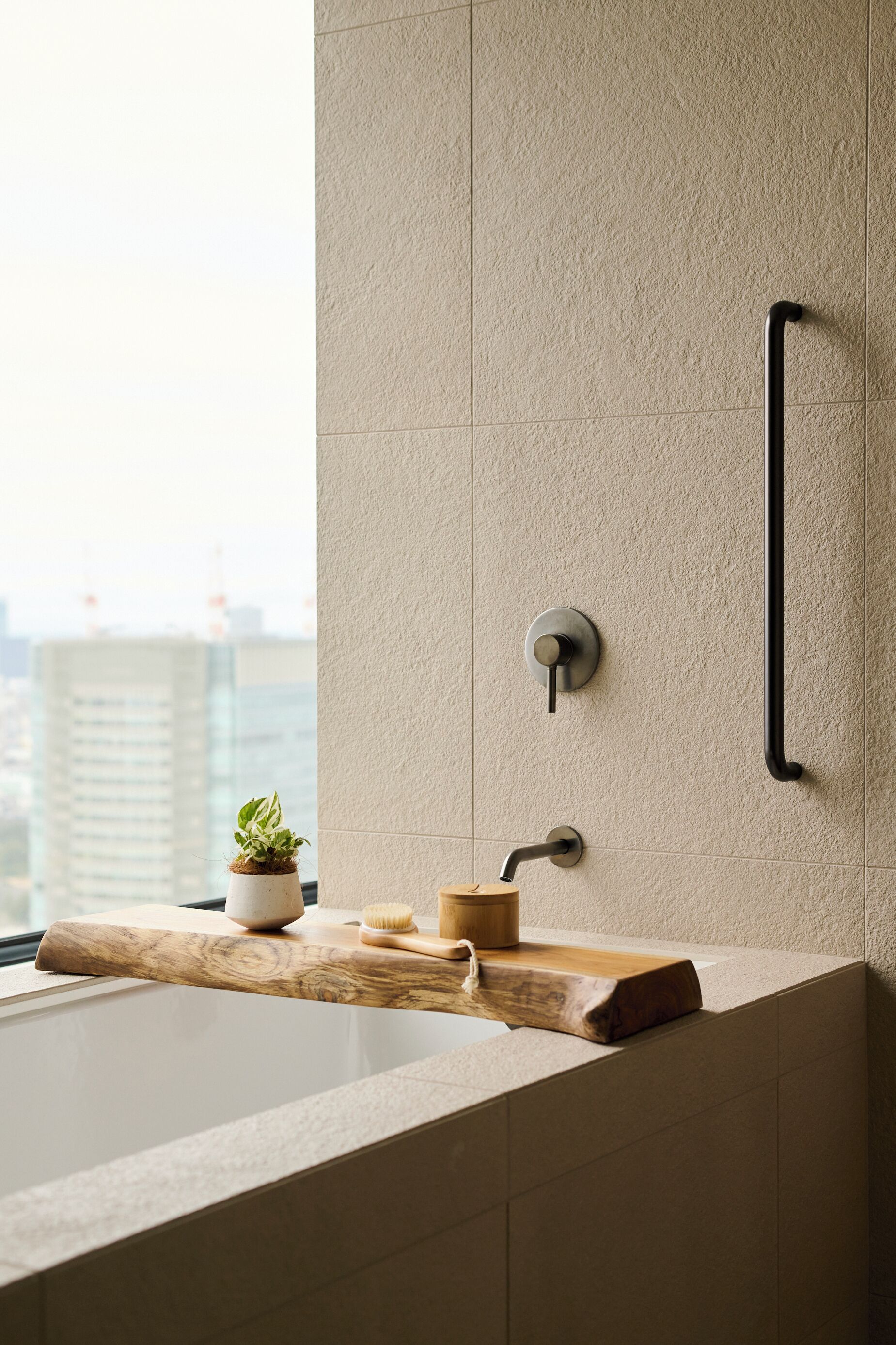Uma casa de banho moderna com banheira, porta-toalhas, planta em vaso e tábua de corte de madeira.