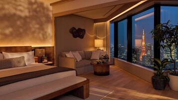 Quarto de hotel moderno com uma cama grande, um sofá, uma mesa de centro e vista para o horizonte urbano à noite.