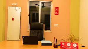 Balcão de recepção com um laptop, um bloco de notas e uma placa vermelha indicando os horários de check-in.
