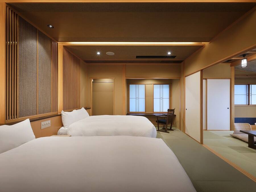 Quarto de hotel com duas camas grandes, uma escrivaninha e um espaço de estar.