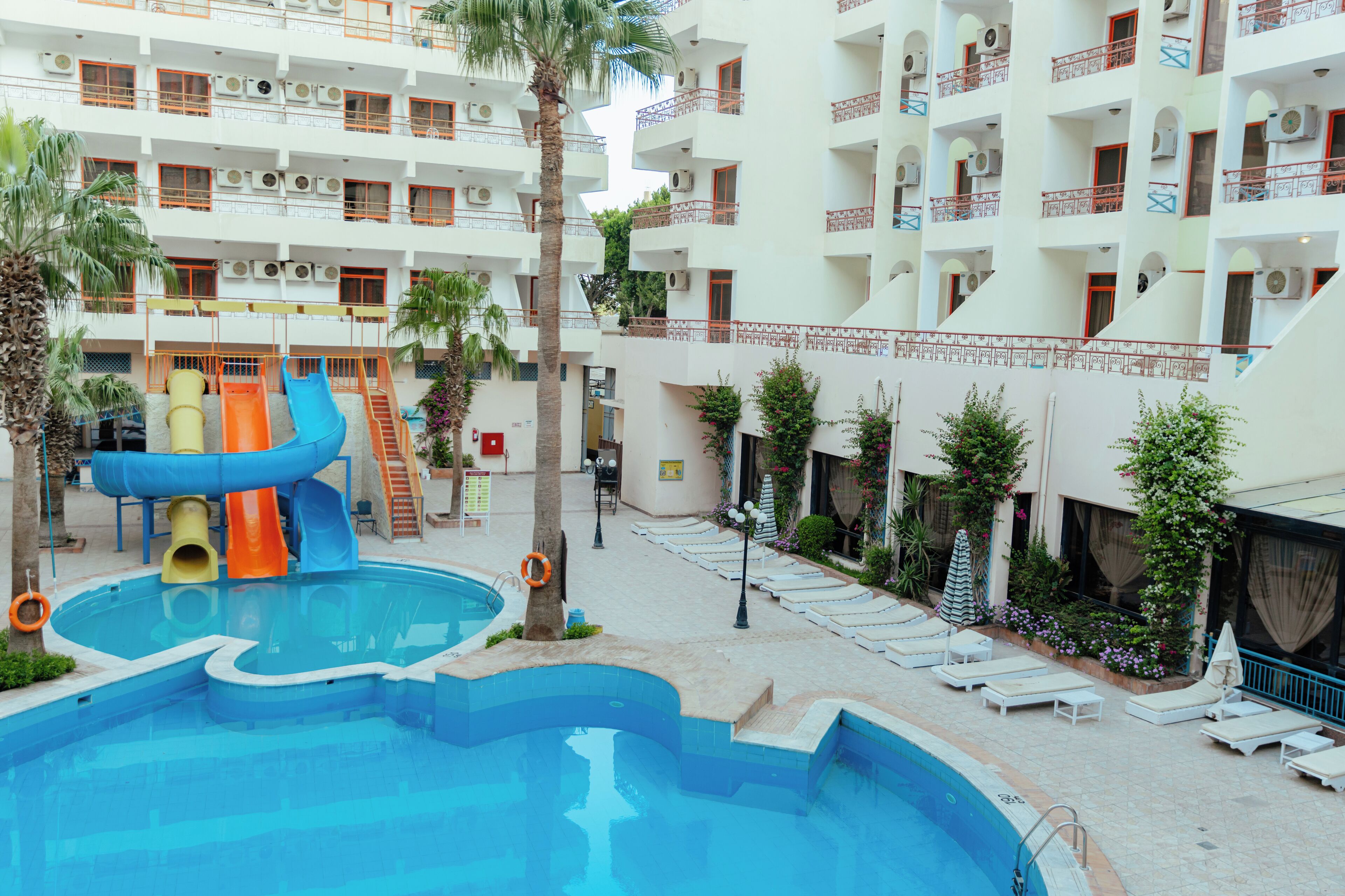 Um hotel com piscina, escorregas e espreguiçadeiras.