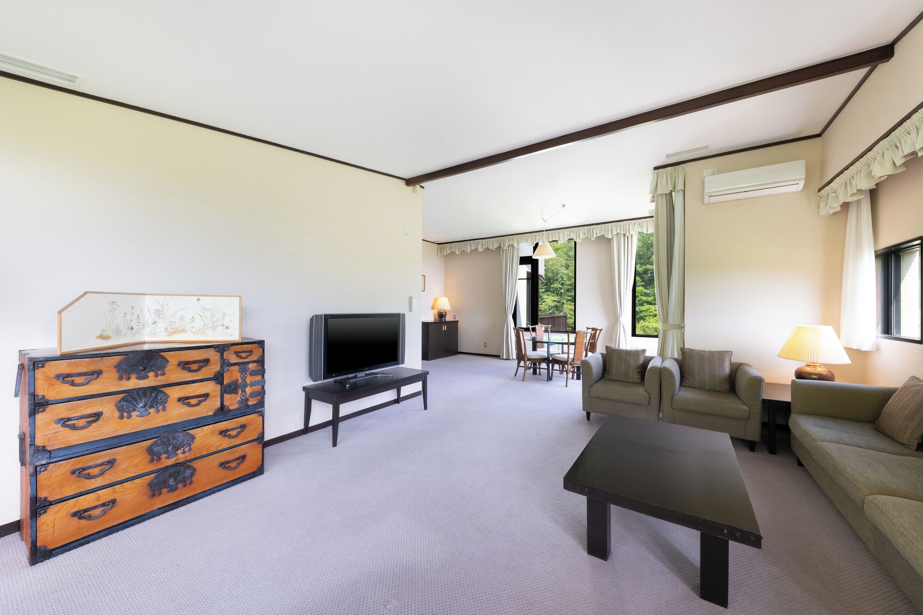 Uma sala de estar ampla com televisão, um aparador de madeira, um sofá e uma mesa de centro.