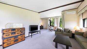 Uma sala de estar ampla com televisão, um aparador de madeira, um sofá e uma mesa de centro.