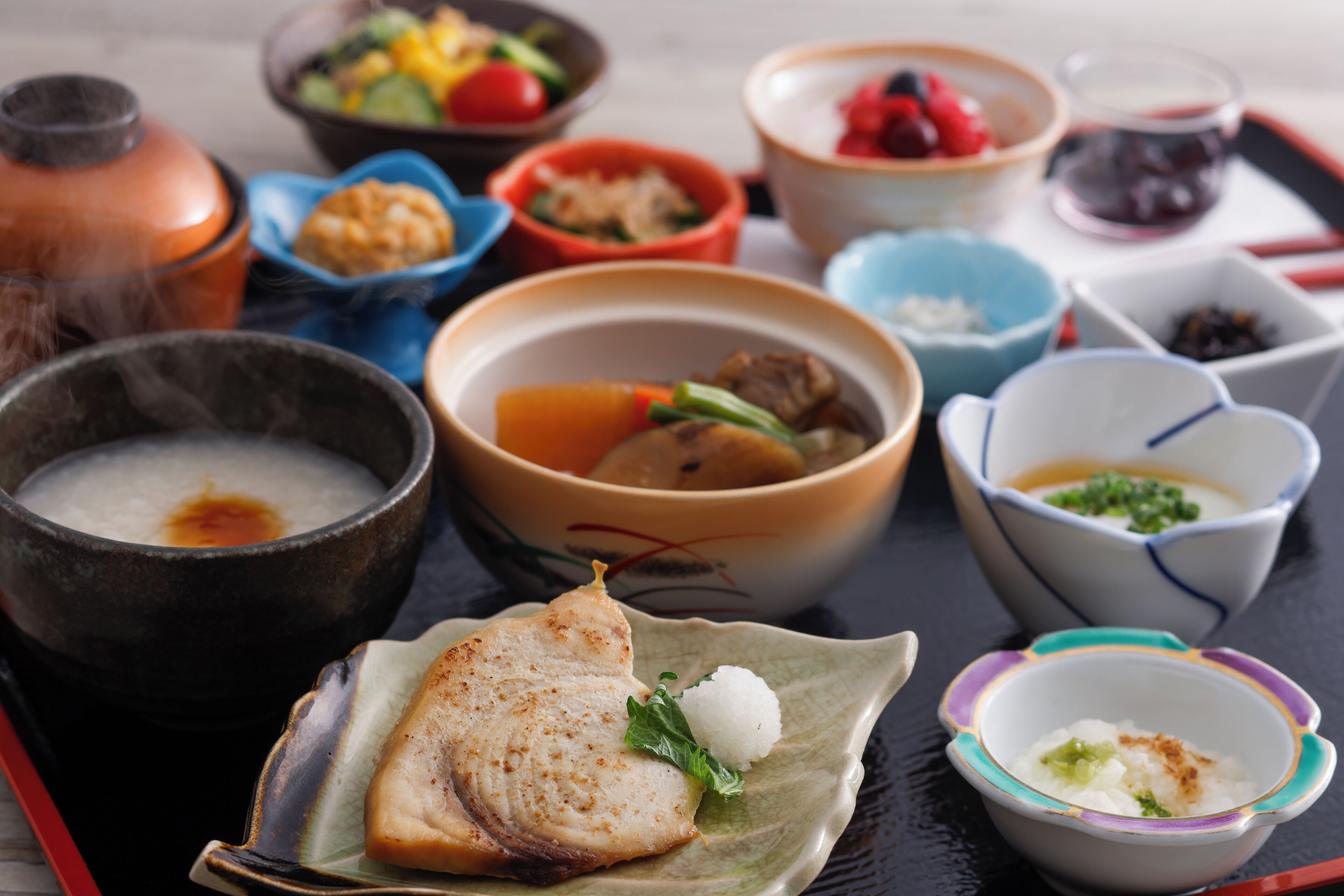Diversos pratos, incluindo uma tigela de sopa, um prato com peixe e várias pequenas porções de diferentes comidas.