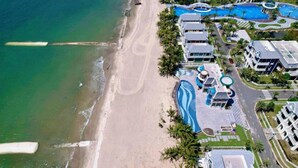 Vista aérea de um resort com praia, piscinas e vários edifícios.