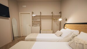 Quarto com duas camas, um guarda-roupa, um espelho e uma mesinha de cabeceira.