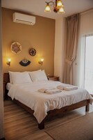 Cama bem arrumada com lençóis brancos, cabeceira de madeira e ar-condicionado fixado na parede.