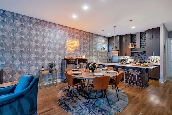 Uma cozinha moderna com ilha central, armários escuros e um letreiro de neon.