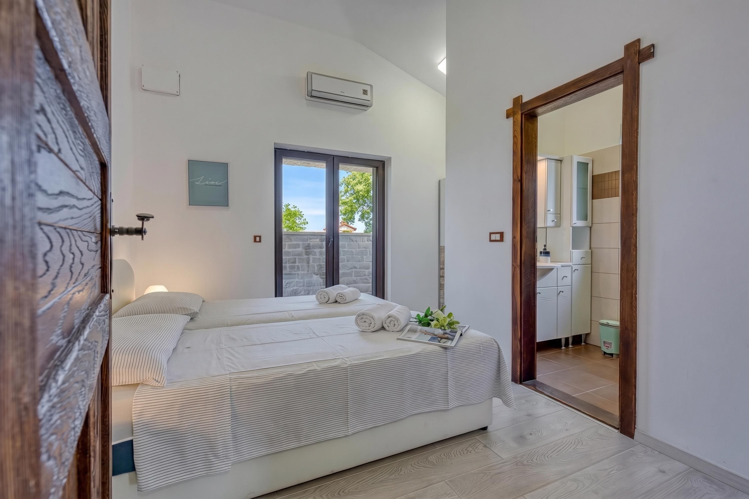 Quarto com cama, janela, porta e espelho.