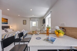 Quarto de hotel moderno com cama, espaço para refeições, cozinha e sala de estar.