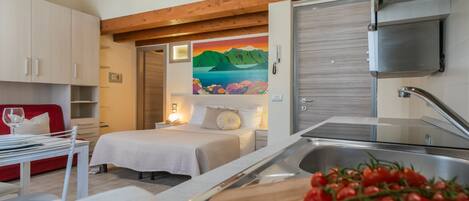 Quarto de hotel compacto com cama, um pequeno espaço de refeições, cozinha compacta e banheiro.
