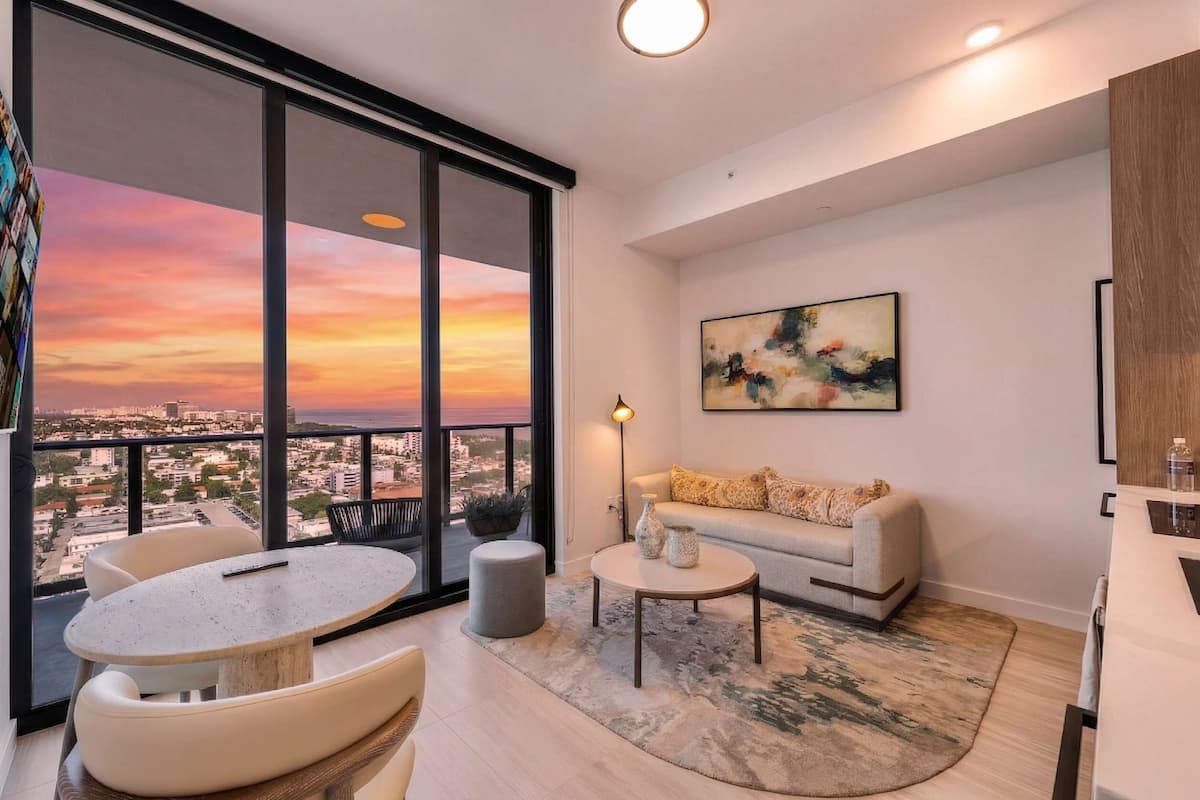Uma sala de estar moderna com uma janela grande, um sofá, uma mesa de centro e um quadro na parede.