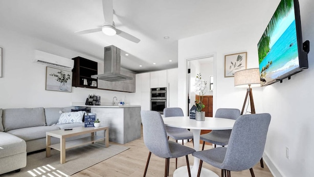 Uma sala de estar moderna com sofá, mesa de centro e área de jantar com cadeiras.