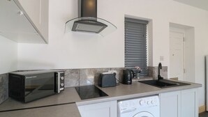 Uma cozinha compacta com micro-ondas, torradeira, chaleira e máquina de lavar integrados.