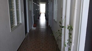 Um corredor comprido e estreito com chão de azulejos e paredes brancas.