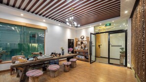 Um interior moderno com teto de madeira, uma mesa de jantar comprida com banquetas e uma porta de vidro que dá para o exterior.