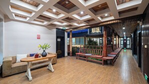 Um hall amplo com piso de madeira, balcão de recepção e área de estar com bancos.