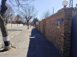 Parede de tijolos com uma placa indicando área de estacionamento e um poste de luz.