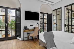 Quarto com cama, escrivaninha e televisão.