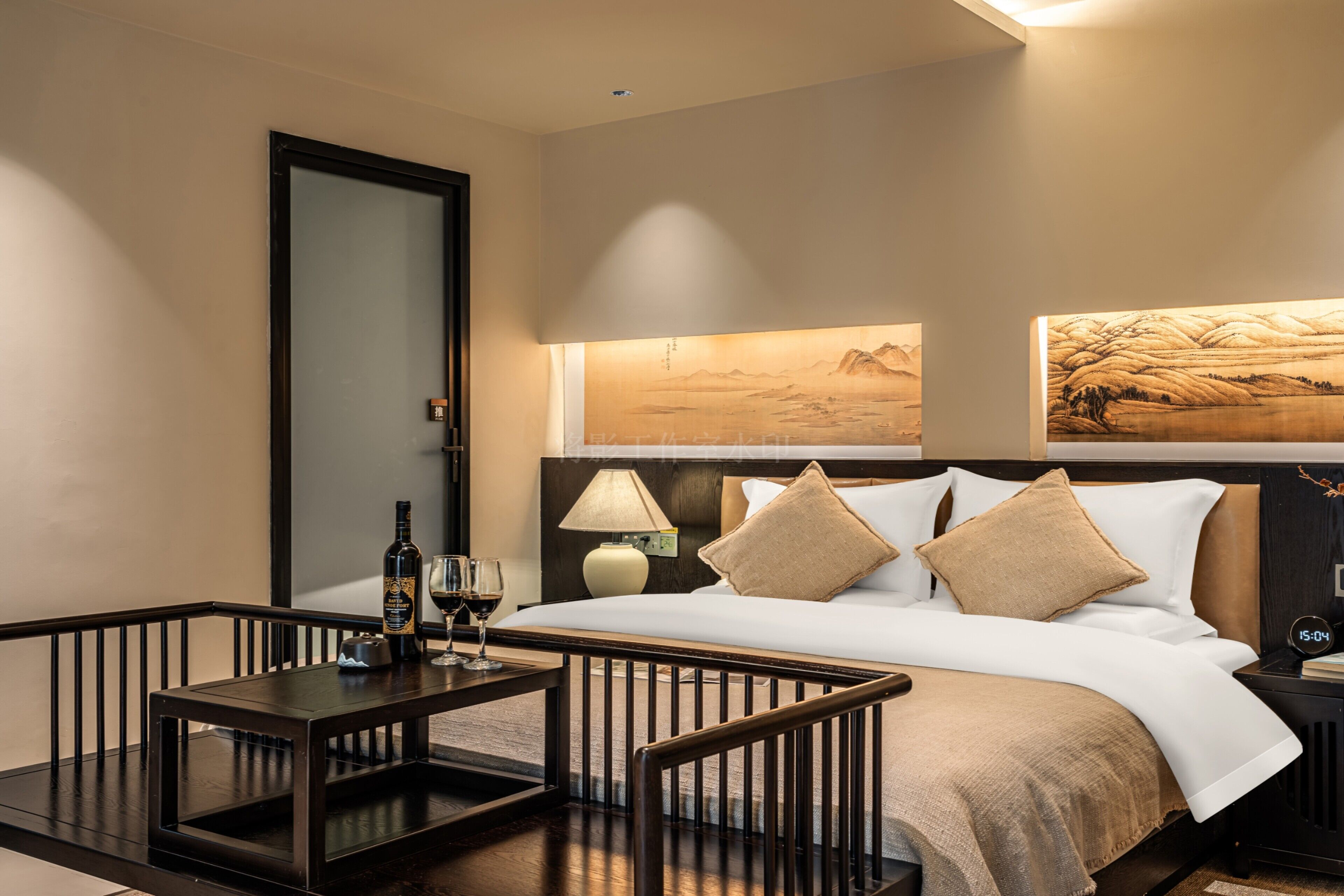 Quarto de hotel com cama, mesa de cabeceira, luminária e obra de arte na parede.