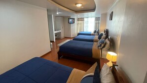Quarto de hotel com duas camas, uma escrivaninha e uma televisão.