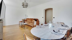Uma sala de jantar moderna com uma mesa redonda posta para seis pessoas, rodeada por cadeiras.