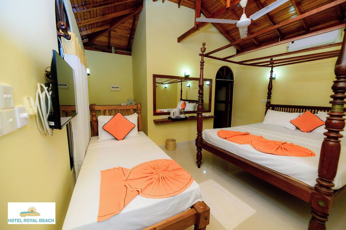 Quarto de hotel com duas camas, teto de madeira, televisão e espelho.