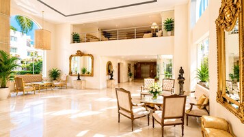 Um hall amplo com teto alto, varanda com pé-direito duplo e área de estar com mesa e cadeiras.
