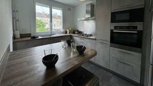 Cozinha moderna com bancada de madeira, eletrodomésticos de aço inoxidável e vista para o exterior.