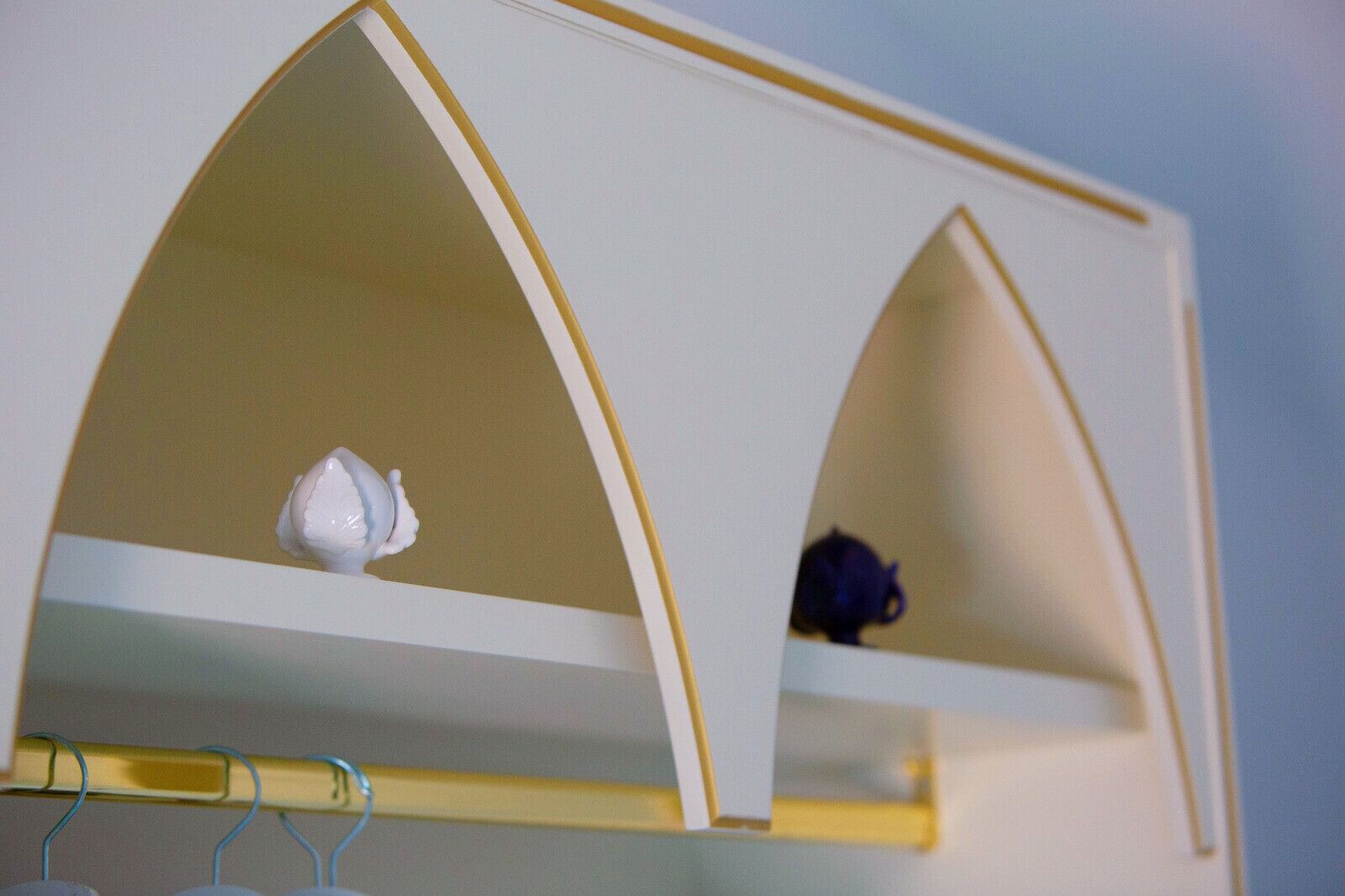Um quarto com duas prateleiras em arco, cada uma contendo um objeto branco e outro escuro.