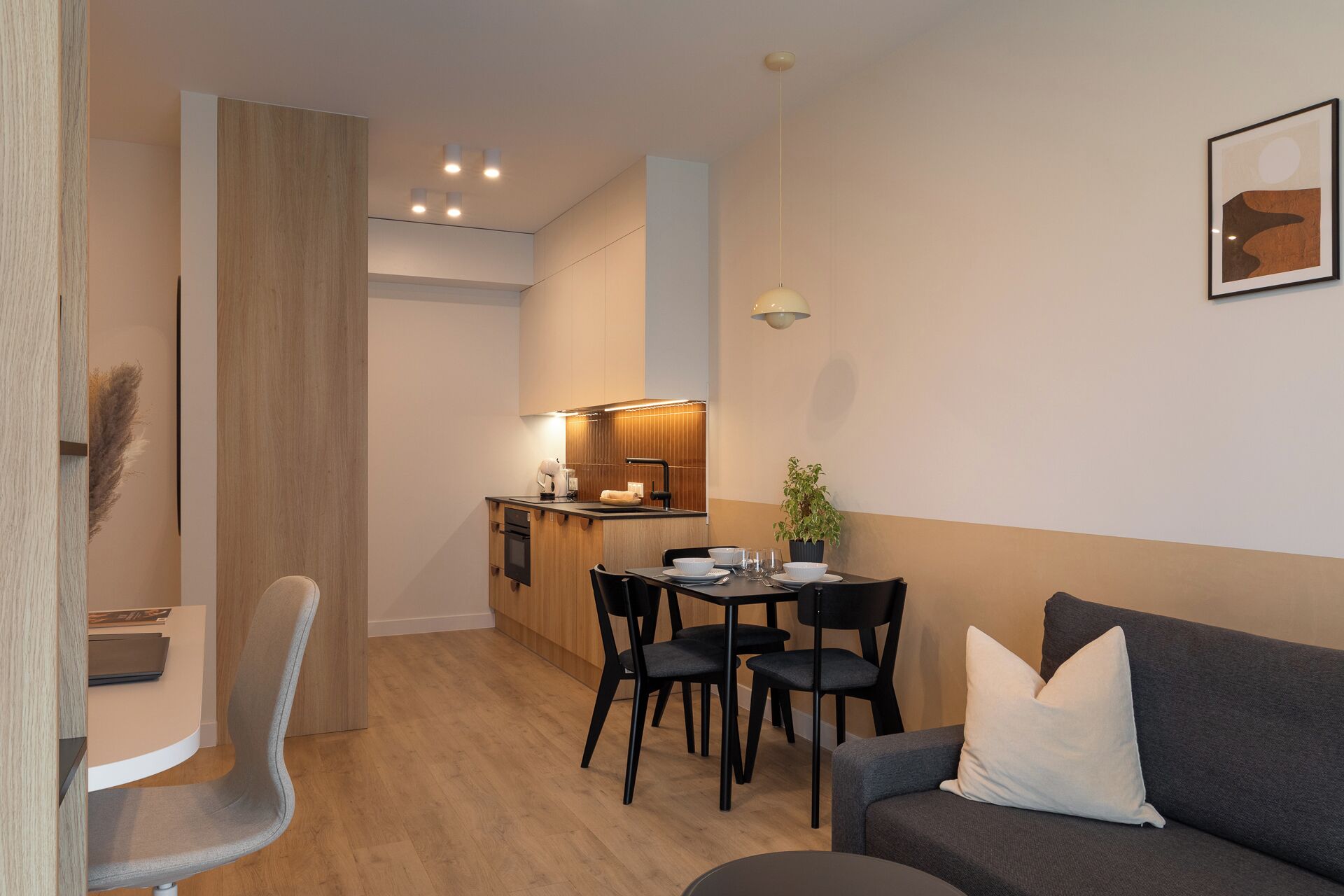 Um espaço compacto com cozinha compacta, área de refeições e sala de estar com sofá e cadeiras.