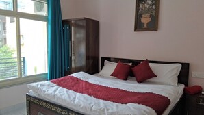Quarto com cama, guarda-roupa, janela com cortinas e um quadro na parede.