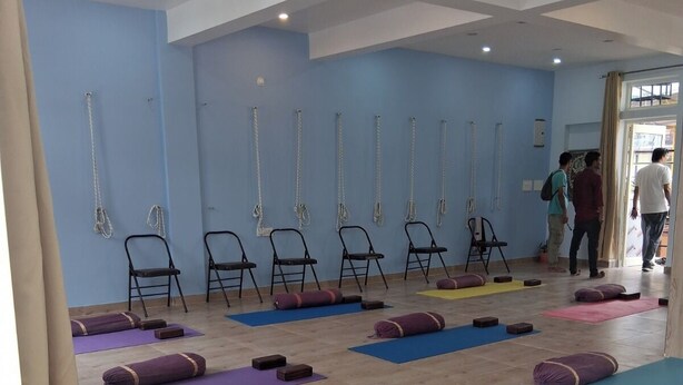 Um estúdio de yoga com tapetes e cadeiras dispostos para a prática.