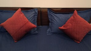Uma cama com cabeceira escura e dois travesseiros vermelhos.