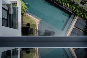 Uma área moderna da piscina ao ar livre, com vista clara para a piscina, vegetação ao redor e um espaço de estar com espreguiçadeiras.