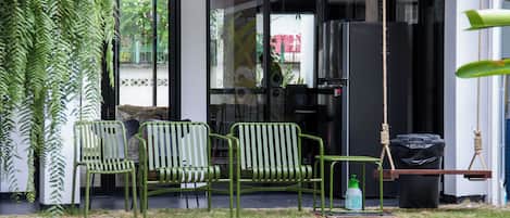 Área da piscina com duas cadeiras verdes, uma mesinha e uma garrafa de água.