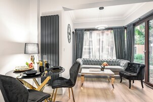 Uma sala de estar moderna com um sofá cinza, cadeiras pretas, uma mesa de centro e uma mesa de jantar com um abajur.