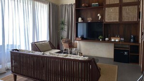 Uma sala de estar com um sofá de madeira, uma televisão e uma estante de livros.