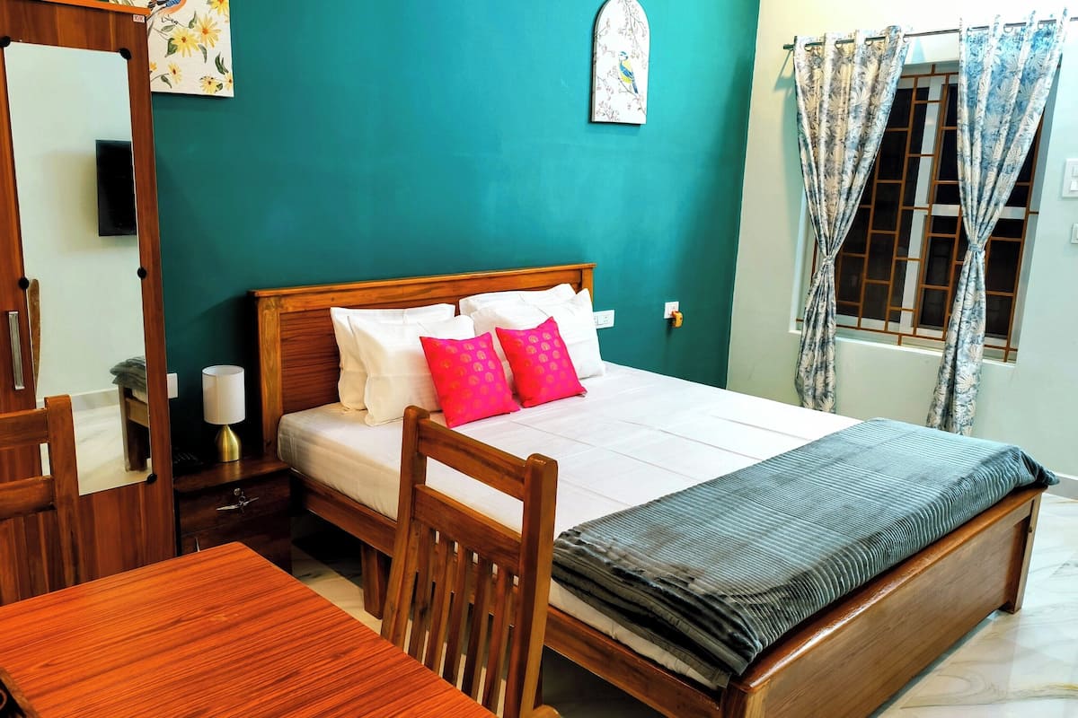Quarto bem arrumado com cama de madeira, mesa de cabeceira e cadeira de madeira.