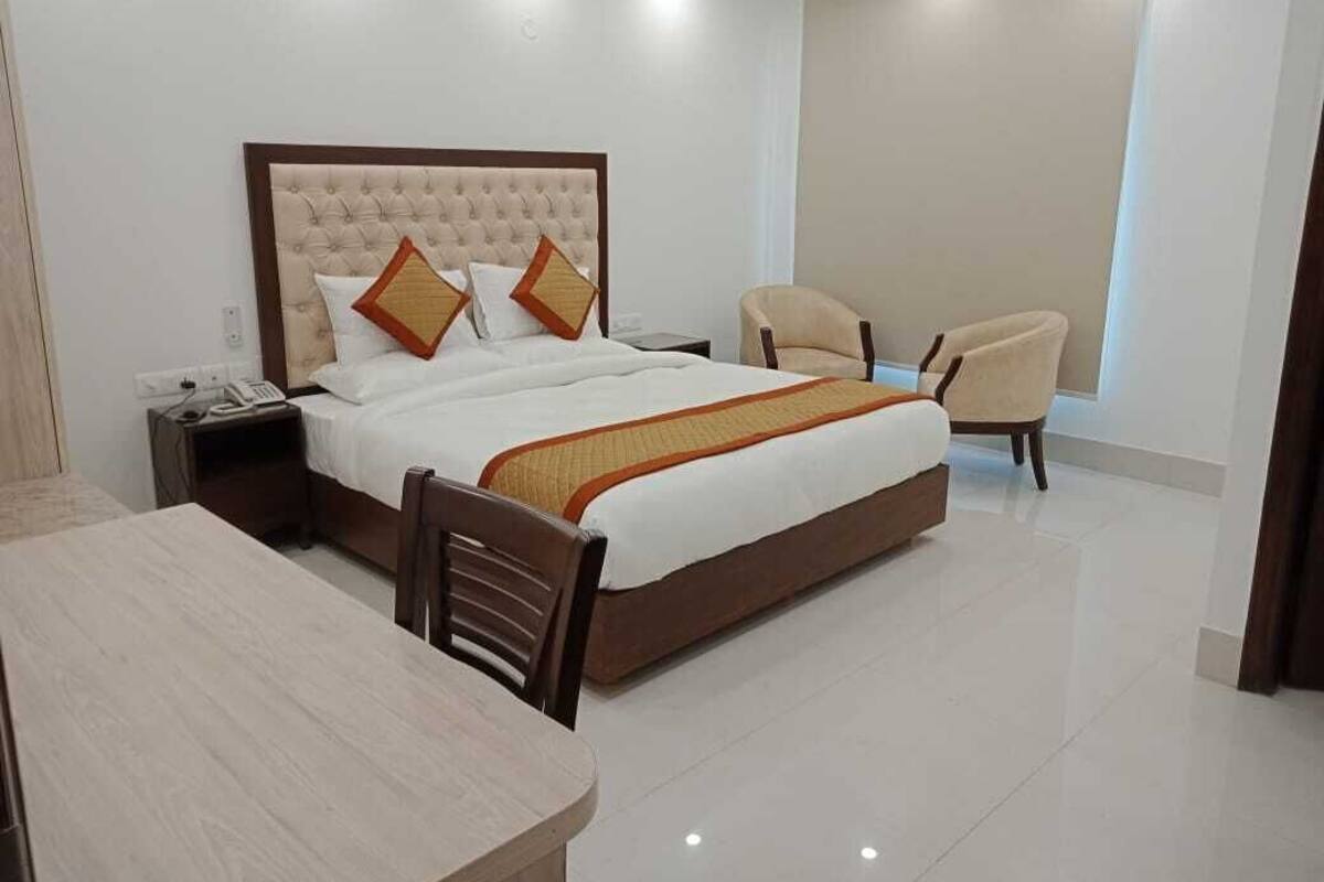 Quarto de hotel com uma cama grande, uma mesa de cabeceira, uma cadeira e uma escrivaninha.