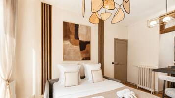 Quarto de hotel com cama, almofadas, toalha, radiador, espelho e porta.