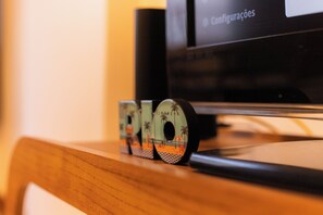Uma secretária de madeira com um monitor exibindo 'configurações' e três suportes decorativos para copos com temas de praia.
