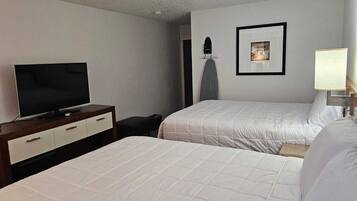 Quarto de hotel com duas camas, uma televisão em uma cômoda, um quadro na parede e um abajur.