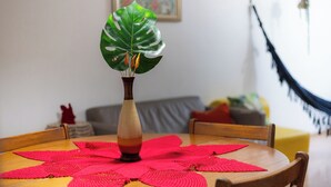 Uma mesa de madeira redonda com um vaso de planta e jogos americanos vermelhos.