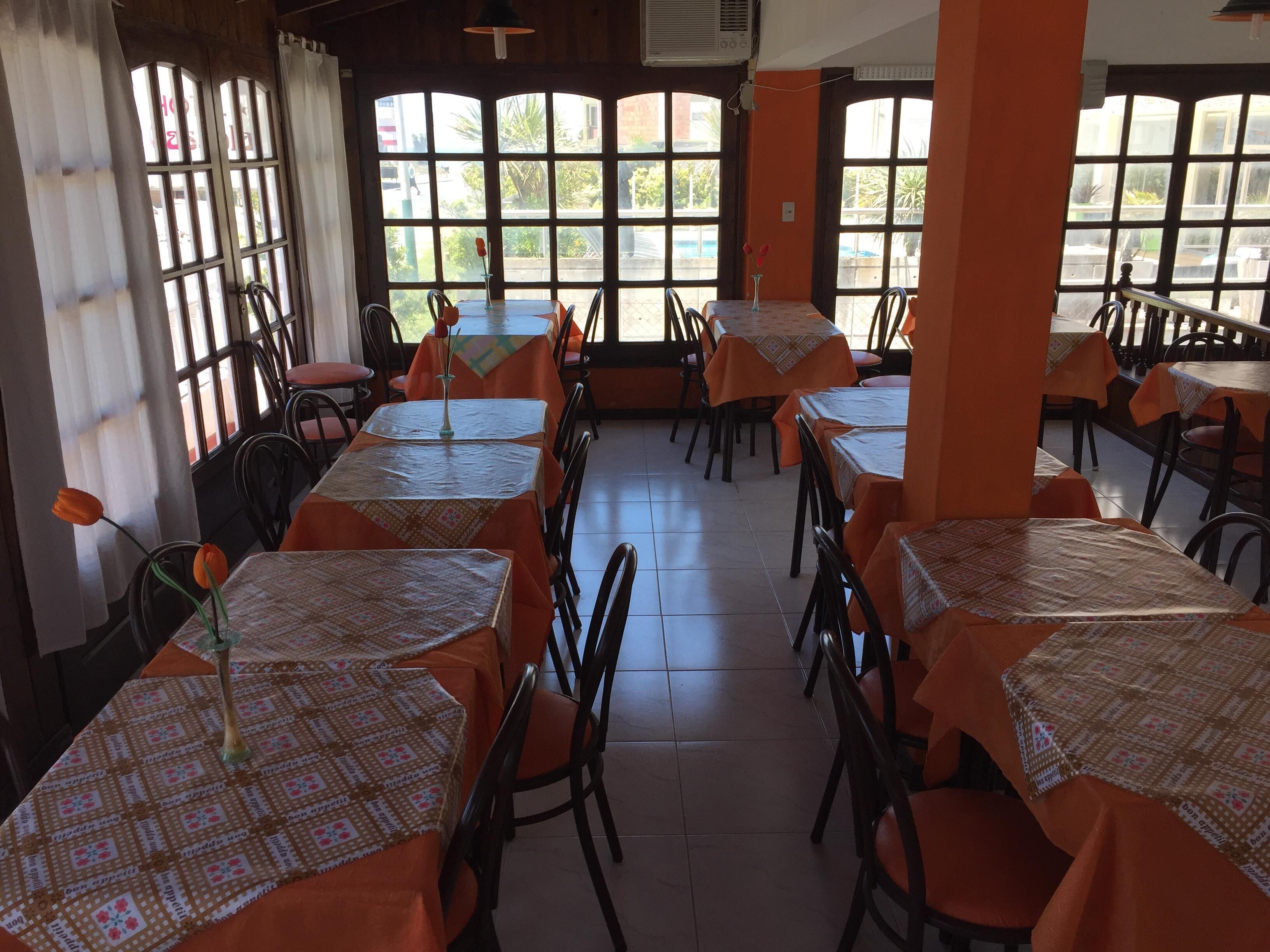 Restaurante com várias mesas cobertas por toalhas de laranja e cadeiras.