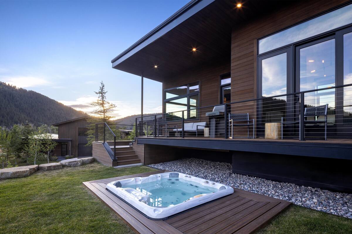Uma casa moderna com hidromassagem, janelas amplas e um deck.