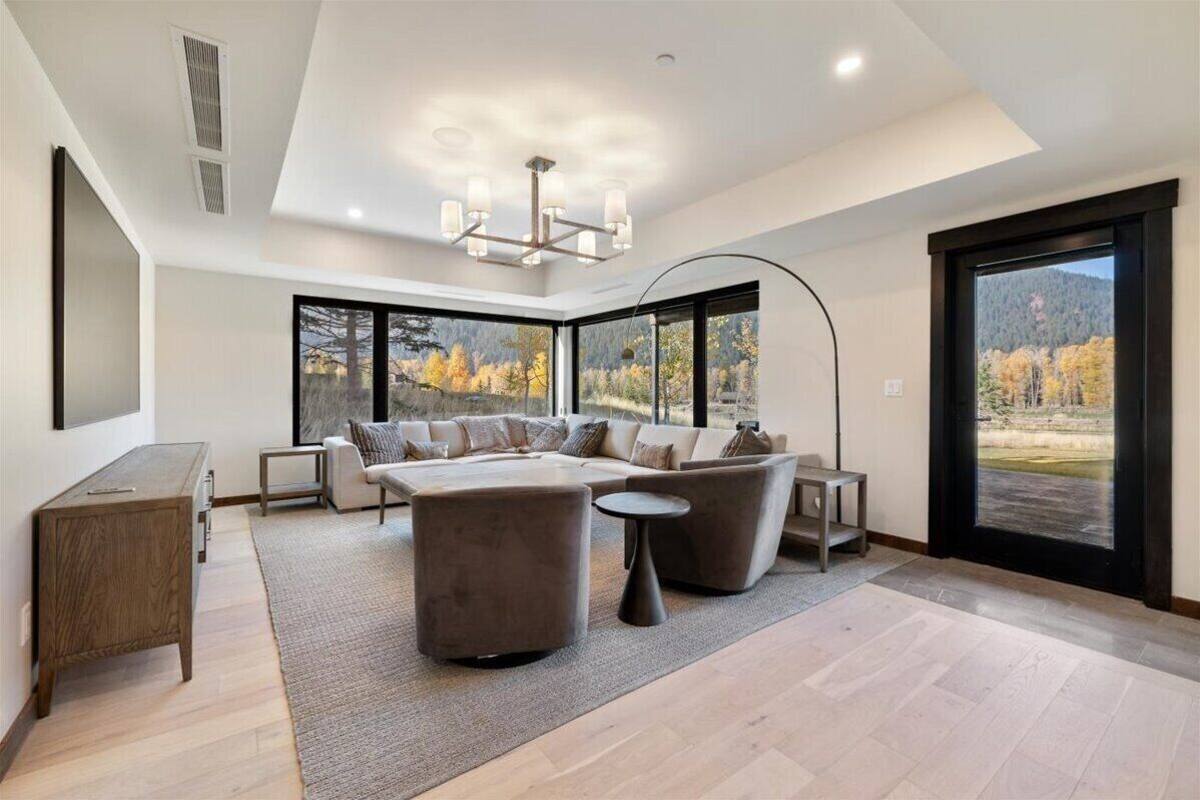 Uma sala de estar espaçosa com um amplo sofá modular, uma mesa de centro redonda e um lustre moderno.
